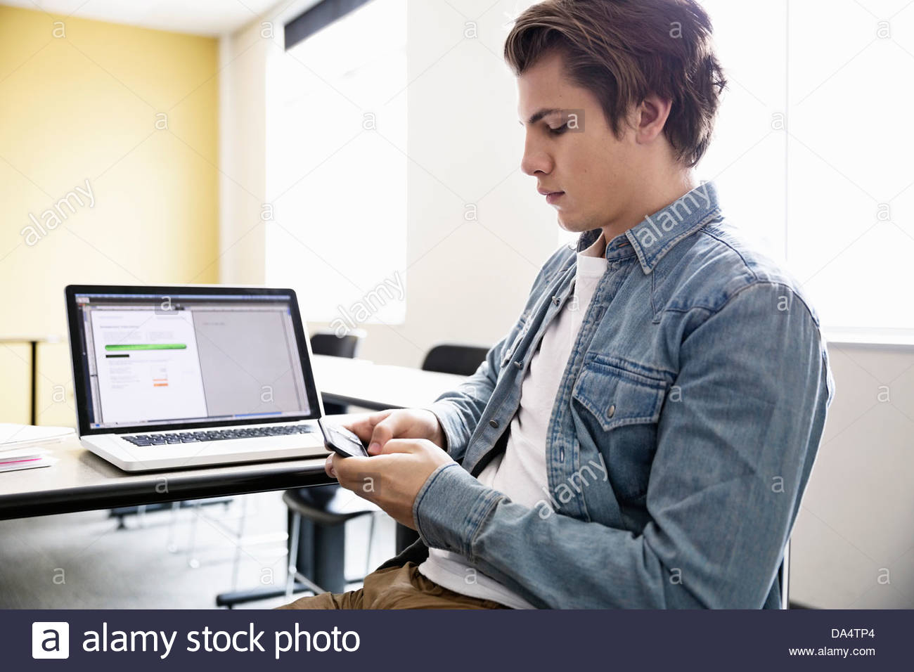 Male student text messaging while sitting in college classroom Stock ...