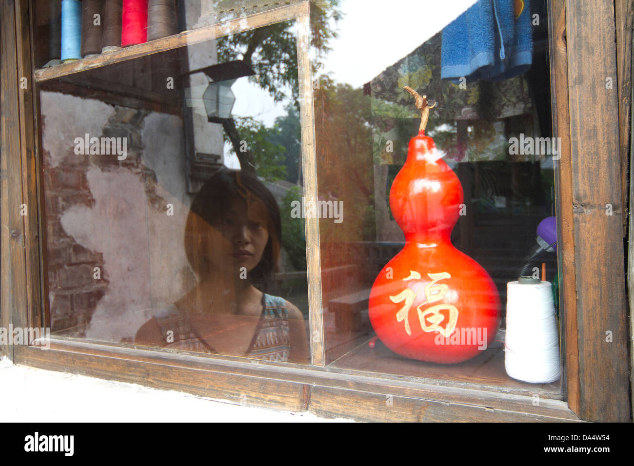 China, Wuzhen, Xizha Scenic Zone, Woman beside shop window displaying ...