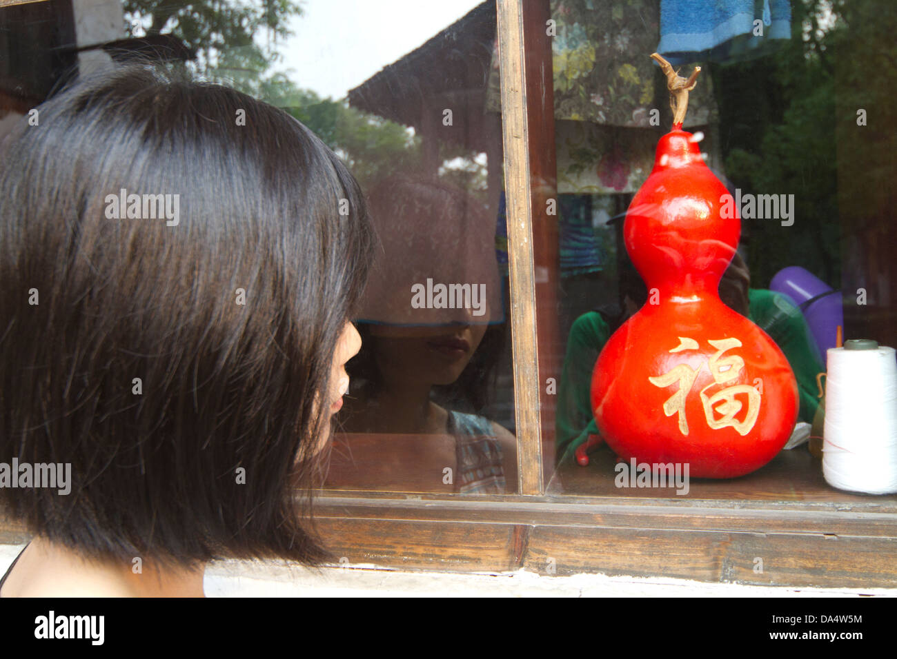 China, Wuzhen, Xizha Scenic Zone, Woman beside shop window displaying ...