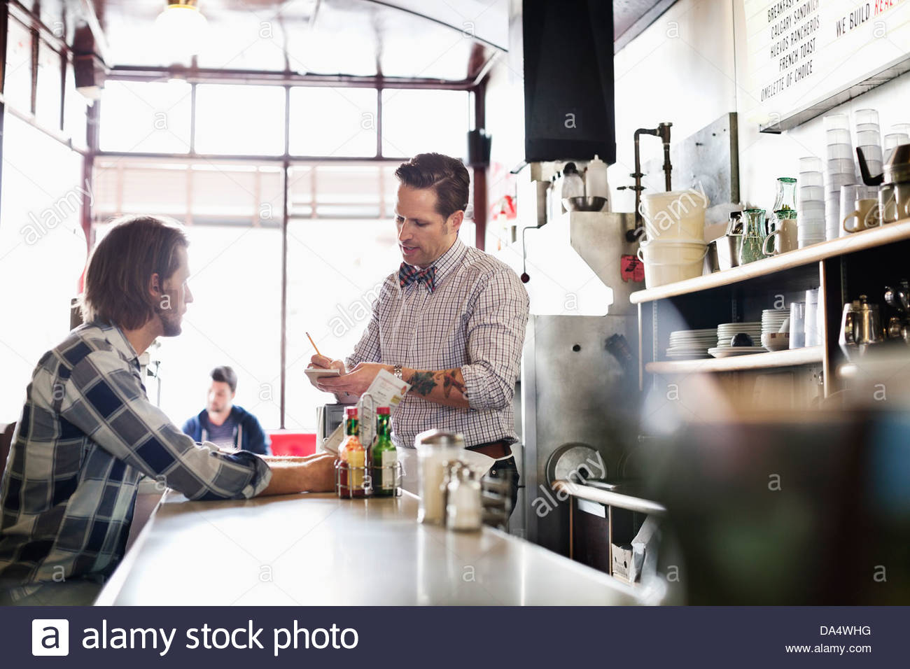 Male business owner taking customer's order at diner counter Stock ...