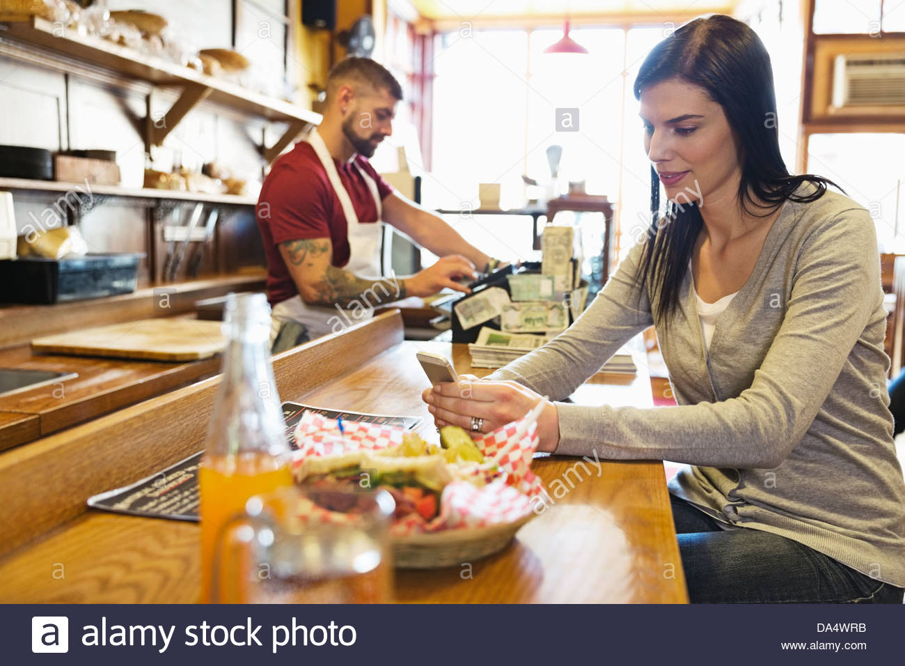 Young woman text messaging at deli counter Stock Photo - Alamy