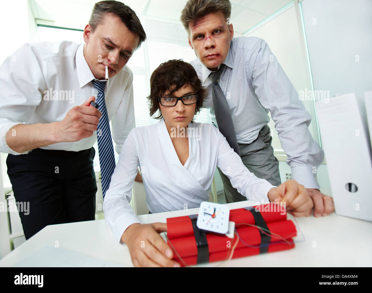Group of businesspeople looking at camera with dynamite on workplace ...