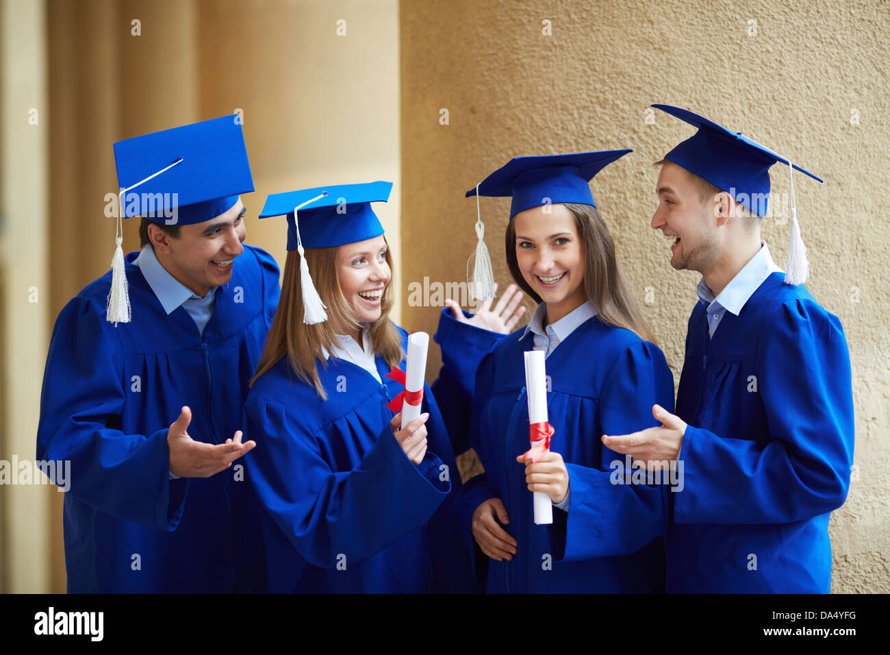 Group of smart students in graduation gowns having chat Stock Photo - Alamy