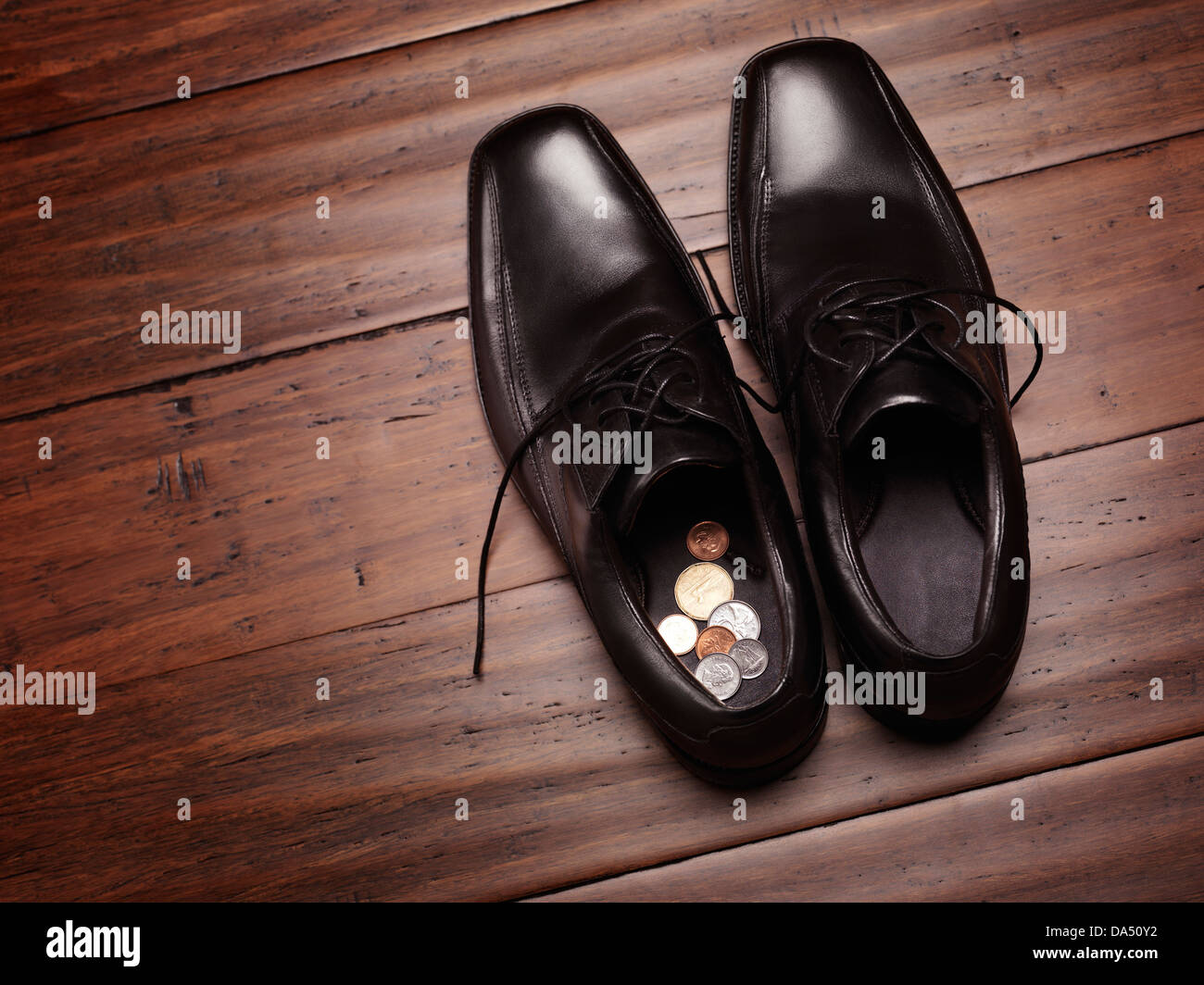 Closeup of mens shoes on the floor with change coins inside. Keeping or ...