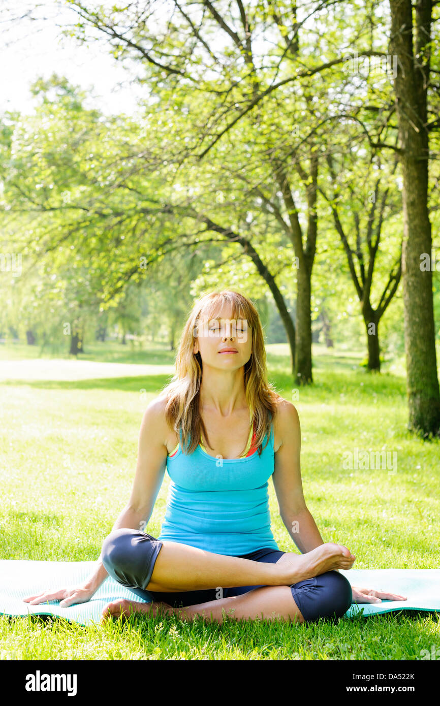 Female fitness instructor in lotus yoga pose outdoor at spring park ...