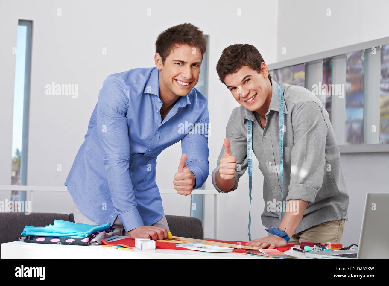 Two happy Fashion designer in their studio holding the thumbs up Stock ...