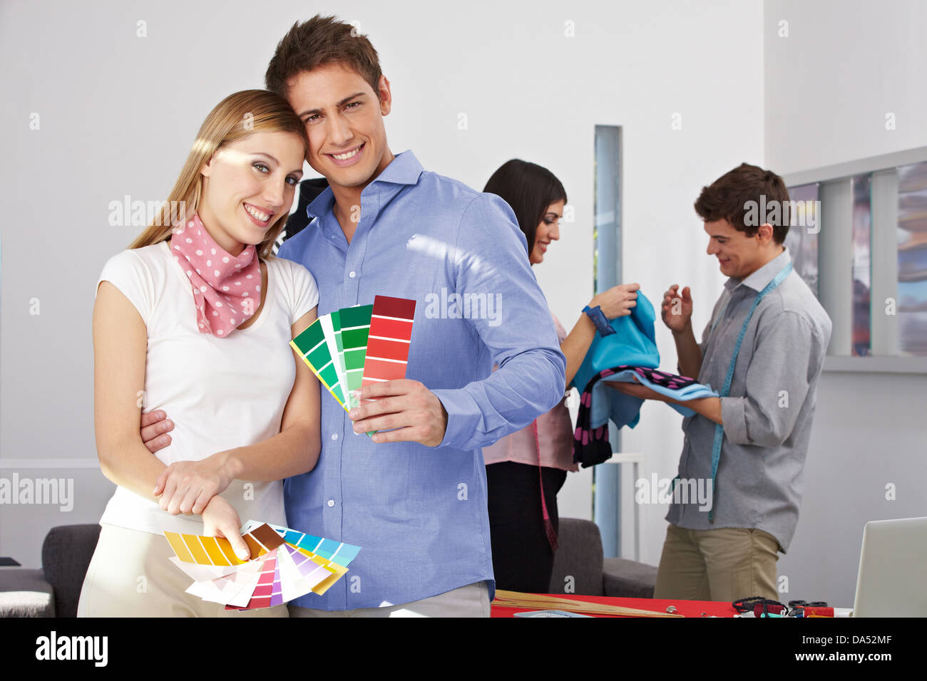 Two happy fashion designer holding color fan samples in their studio ...