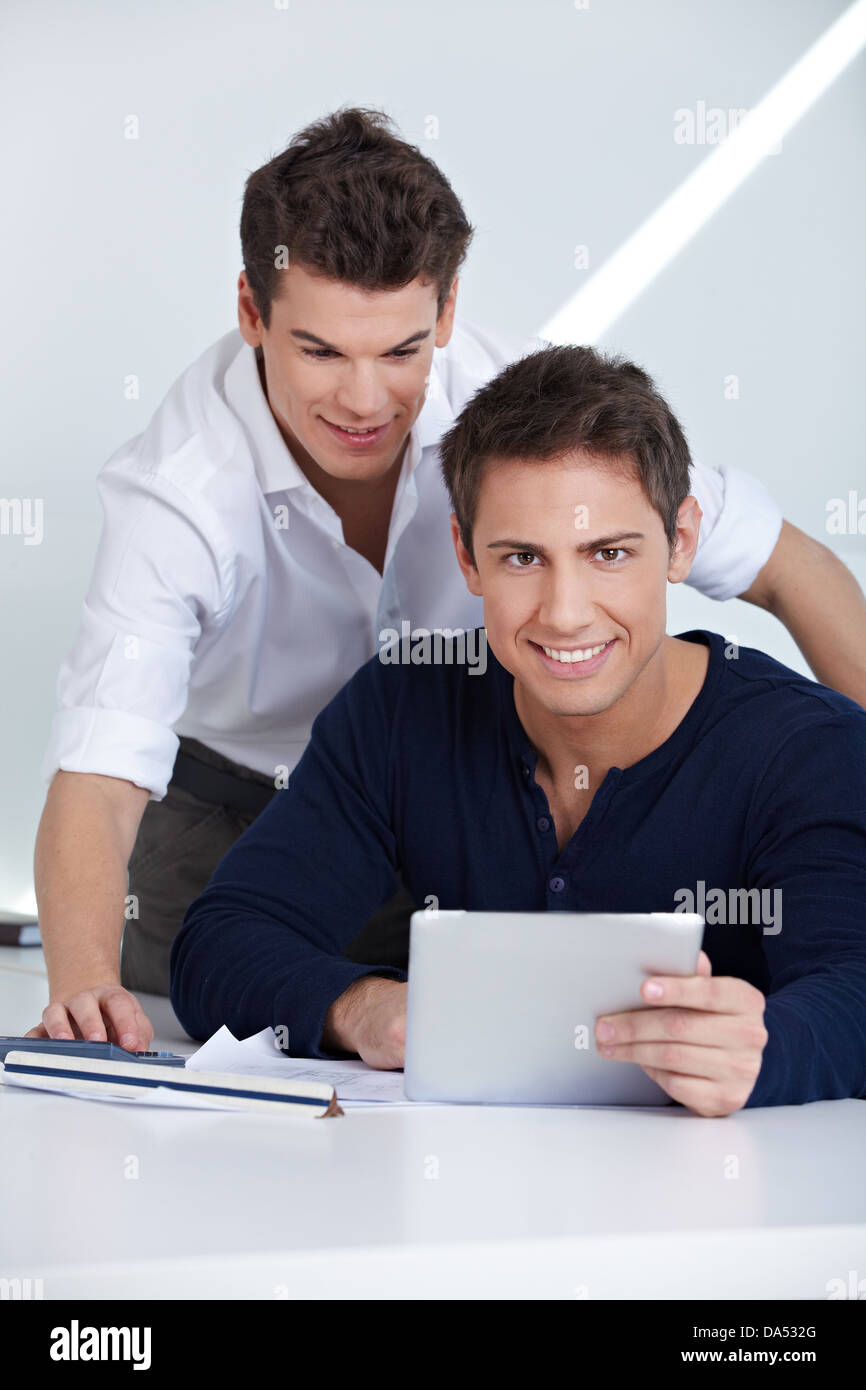 Two business people sitting with a tablet computer at their desk in the ...