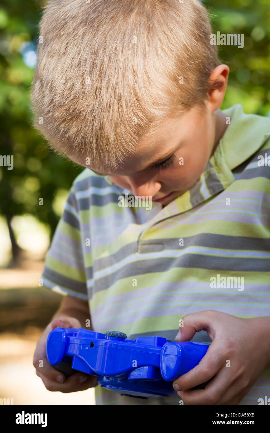Boy (4-5) playing handheld video game, France Stock Photo - Alamy