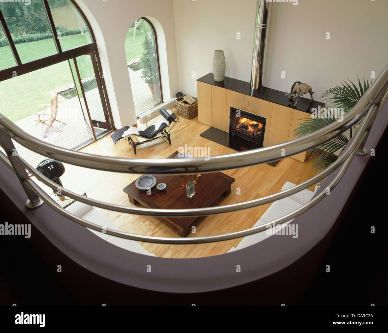 Chrome banisters on landing with view of modern living room with wooden ...