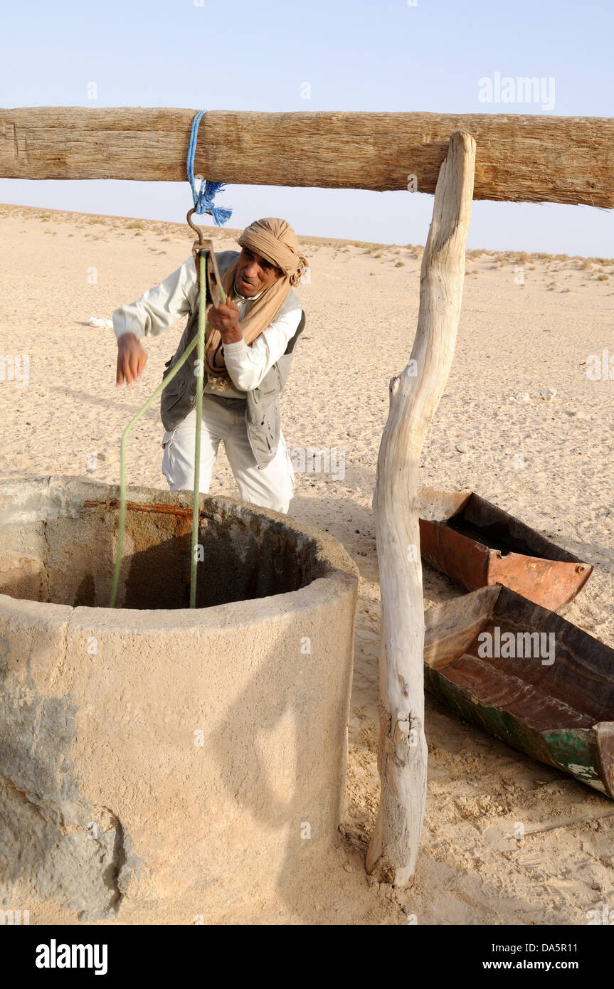 Tunisian man pulling water from a well in the Sahara Desert near Tozeur ...