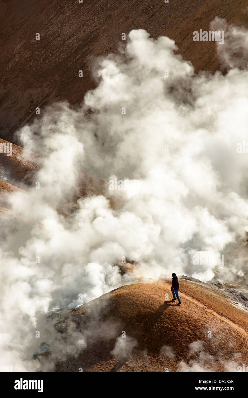 Lone person walking up a mountain through a steaming geothermal ...