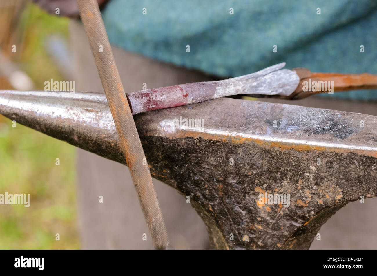 A blacksmith uses a file to shape a piece of red-hot iron Stock Photo ...