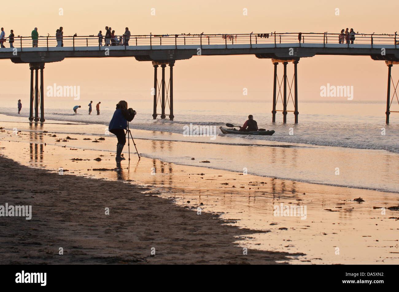 Colourful summer sunset sky & view of people walking on seaside pier ...