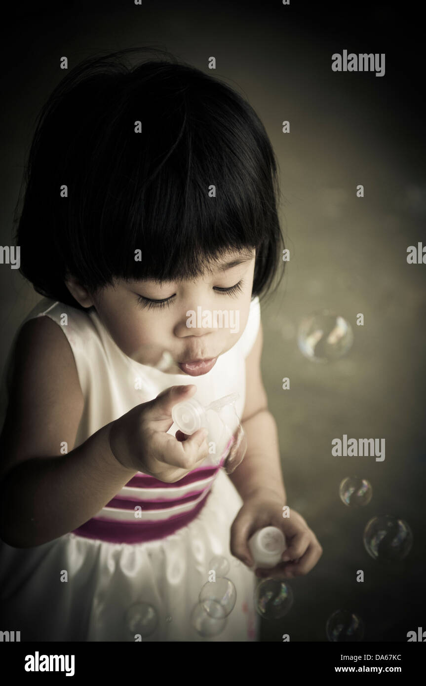 Little Asian girl blowing bubbles in a dress Stock Photo - Alamy