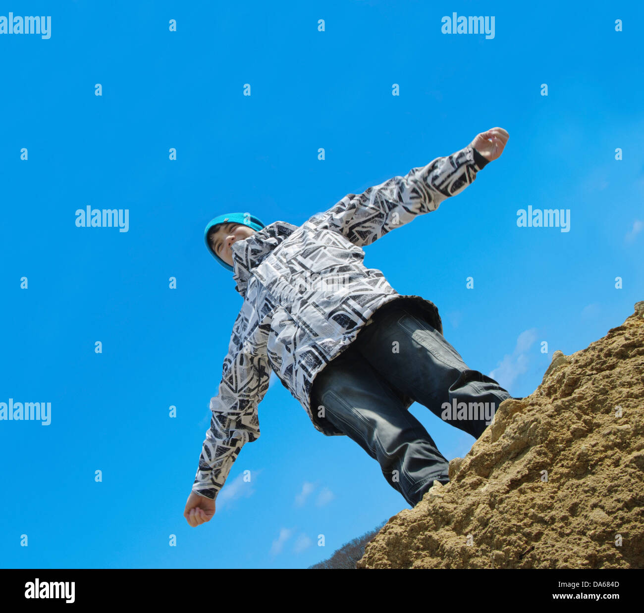 young man flying above a rock on blue sky background Stock Photo - Alamy