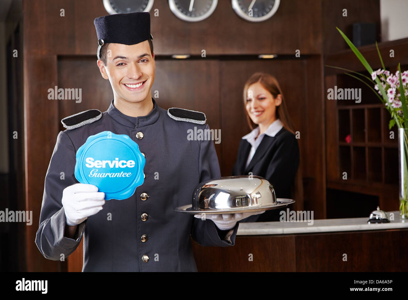 Smiling concierge in hotel reception holding service sign Stock Photo ...