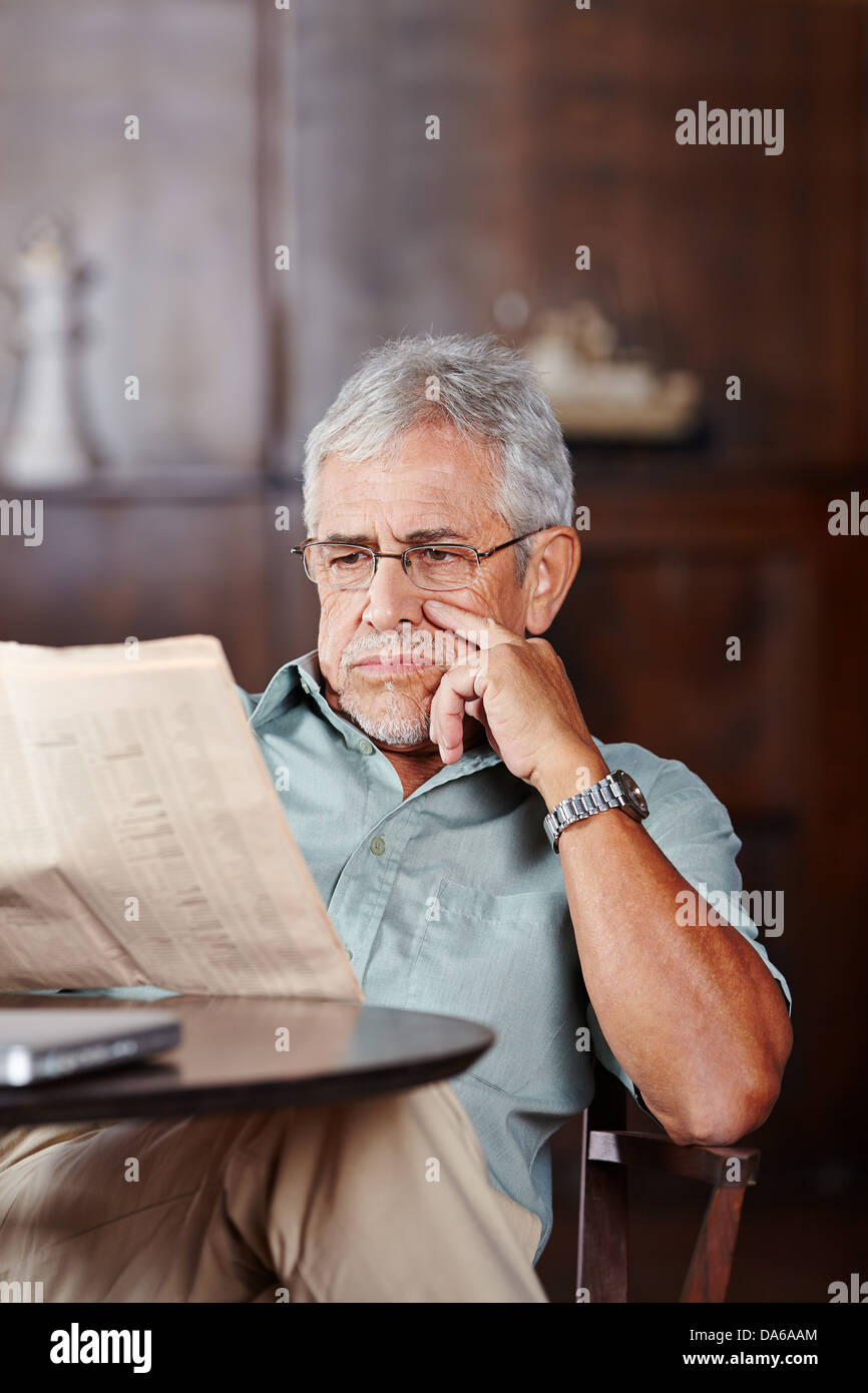 Senior man reading a newspaper at table in retirement home Stock Photo ...