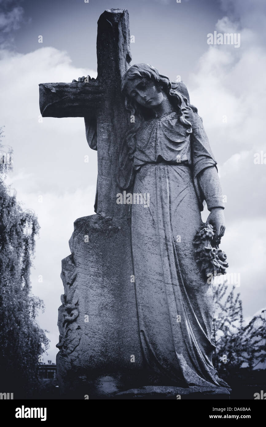 Angel leaning on cross Stock Photo - Alamy