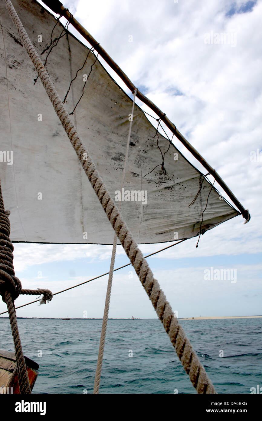 A closeup of a traditional dhow sail and ropes on emerald blue water in ...