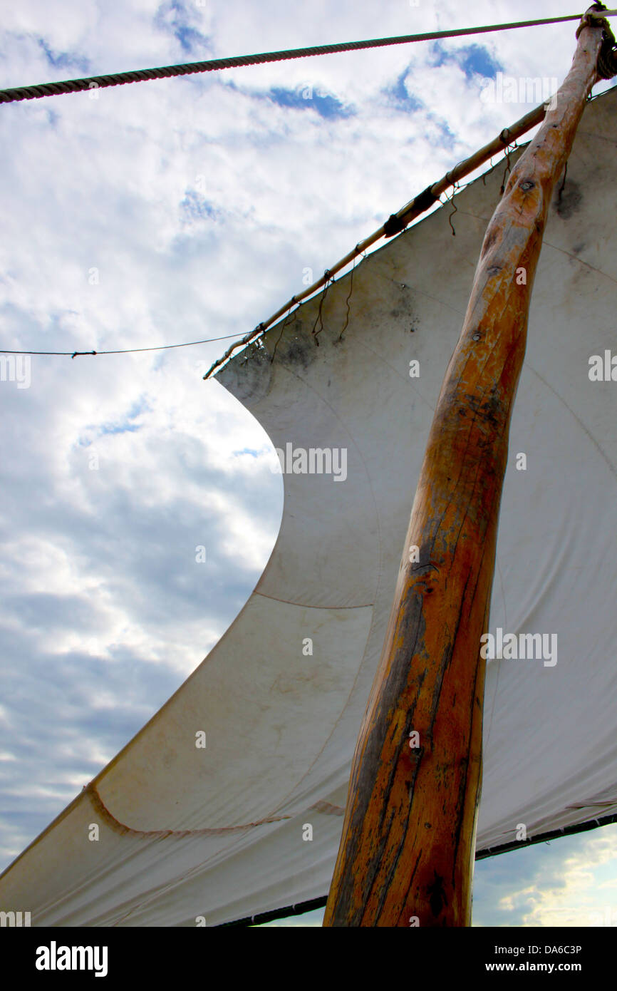 A closeup of a traditional dhow sail and rope rigging on blue sky cloud ...
