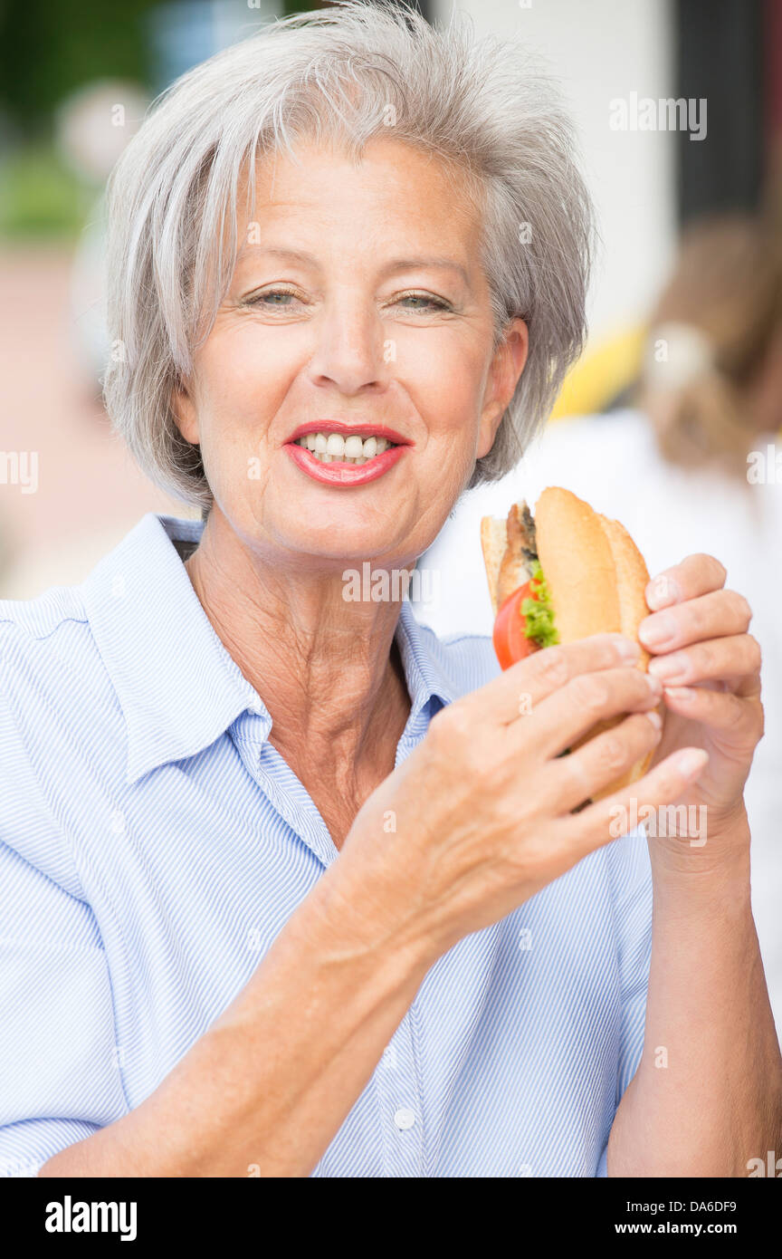 Smiling senior woman eating some fish Stock Photo - Alamy