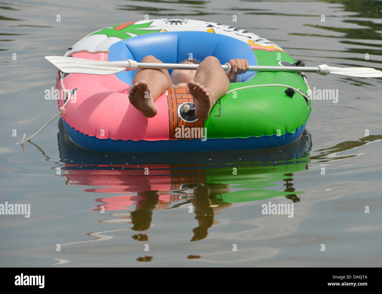 A youth lies in a rubber raft on a bathing lake in Gernsheim, Germany ...