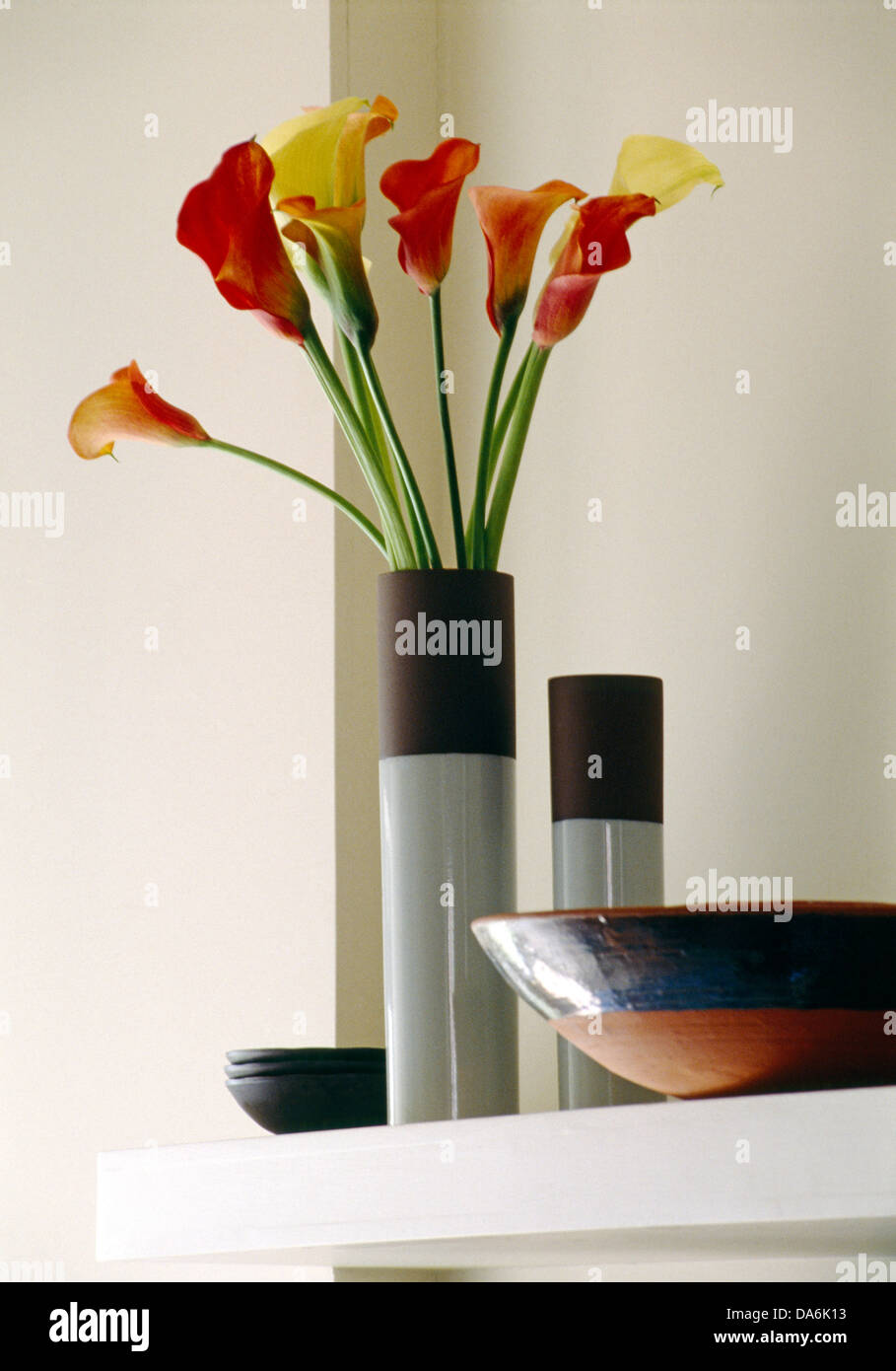 Arrangement of red and yellow arum lilies in stoneware vase Stock Photo ...