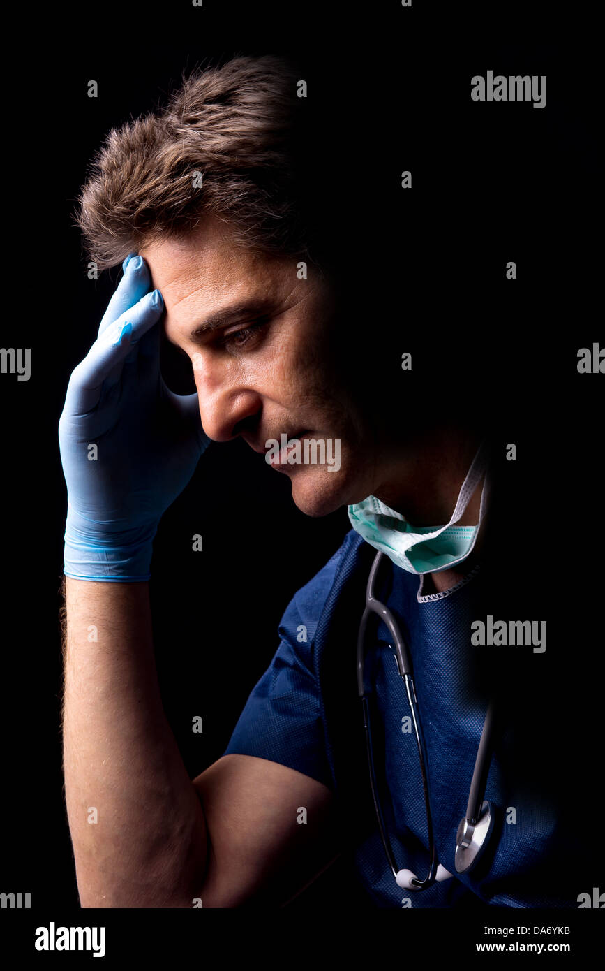 Tired doctor in uniform isolated against a black background Stock Photo ...