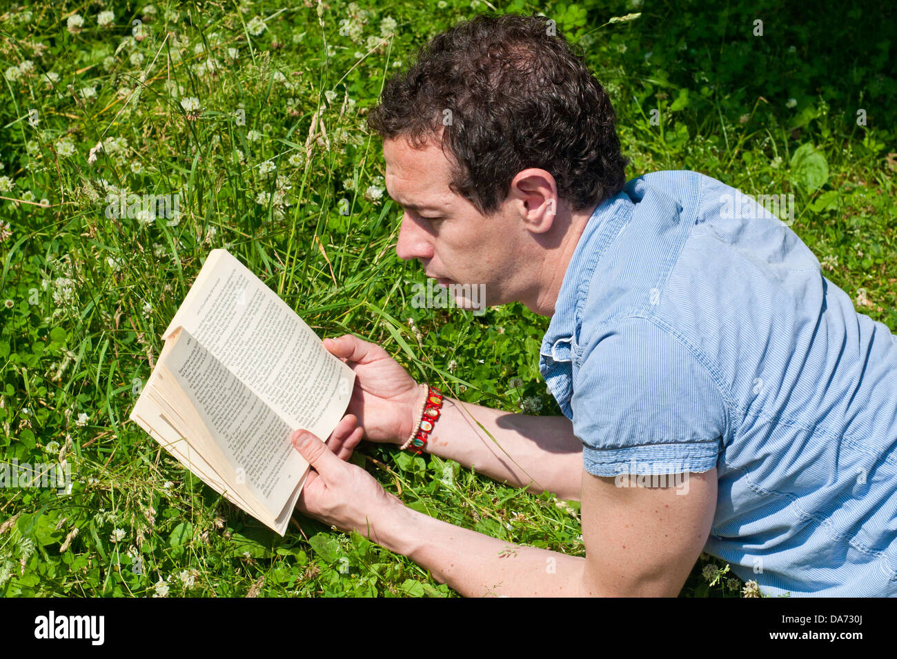 A man reading a book in his garden in summer Stock Photo - Alamy