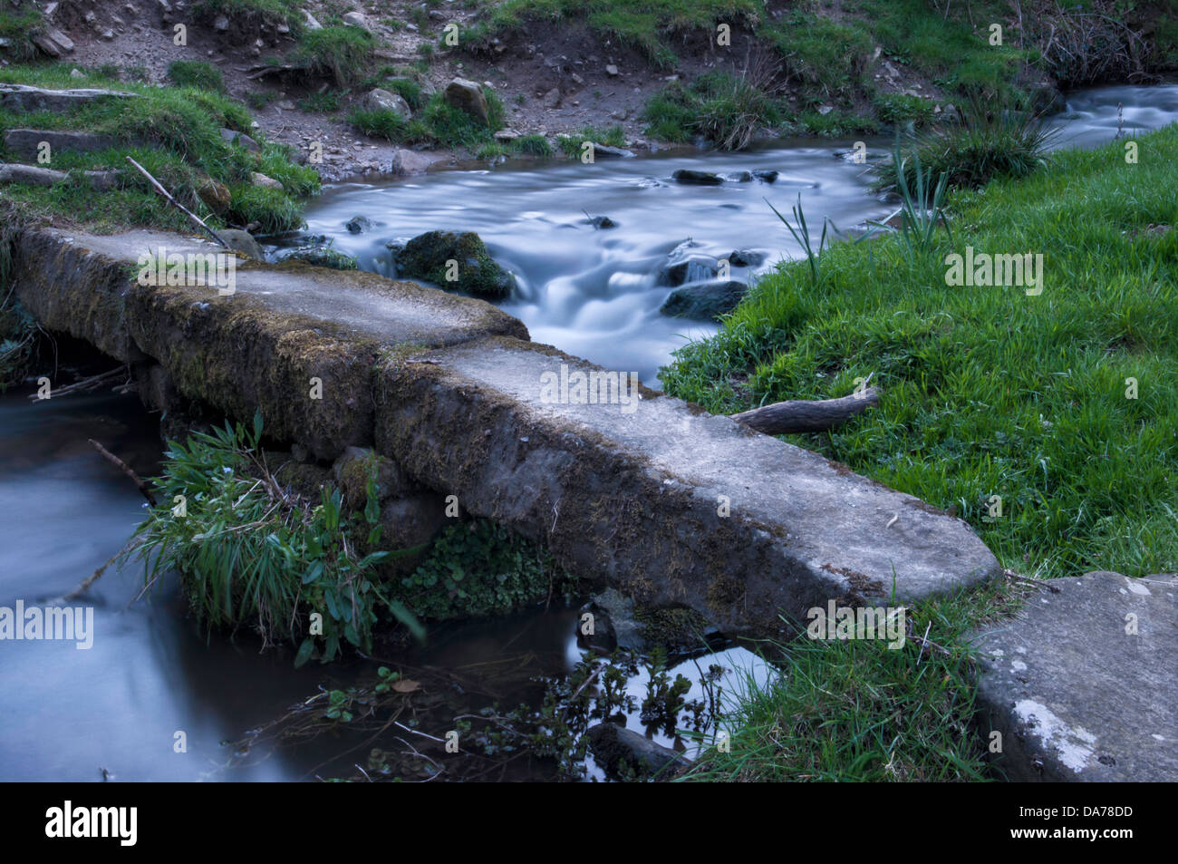 A stone bridge over a stream at twilight Stock Photo - Alamy
