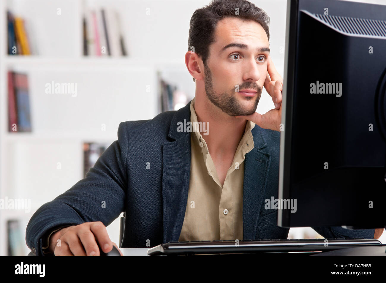 Surprised man looking at a computer screen, thinking about the job at ...