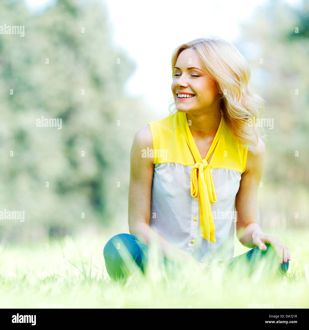 Beautiful happy young woman sitting on grass Stock Photo - Alamy