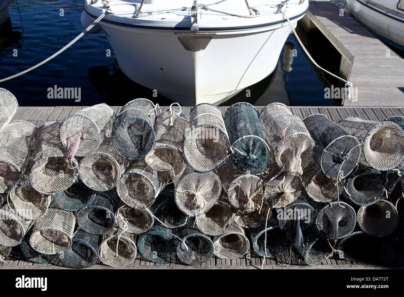 Shellfish pots on a quay with boat Stock Photo - Alamy