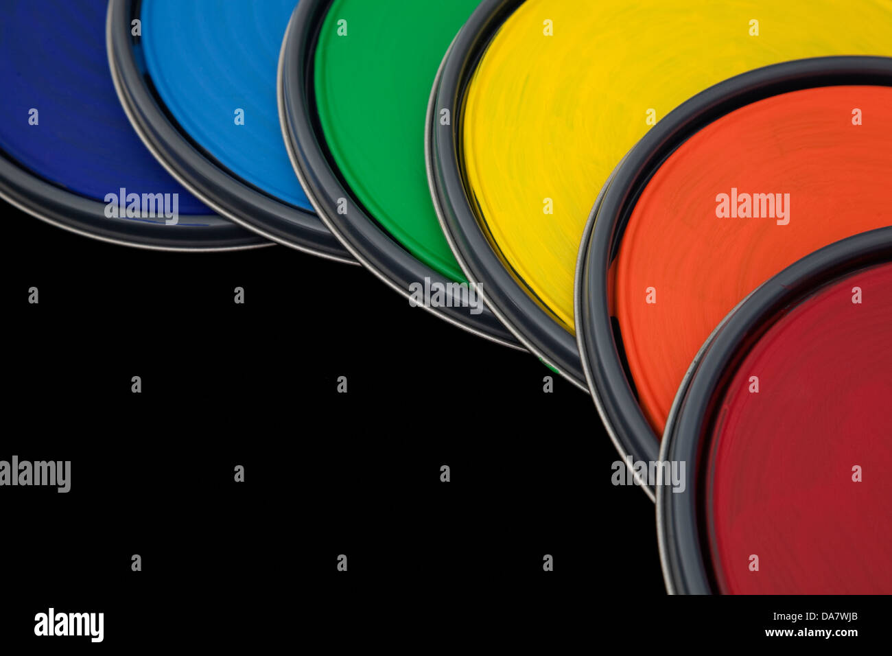 Brightly painted paint can lids with primary colors on black background ...