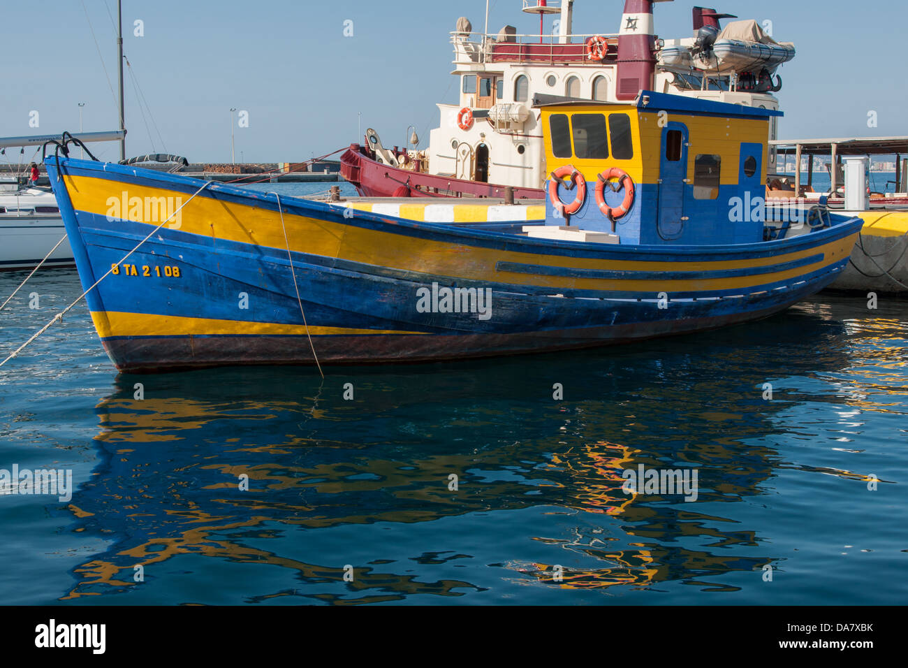 Photograph of a colorful yellow and blue boat harbored in the Costa ...