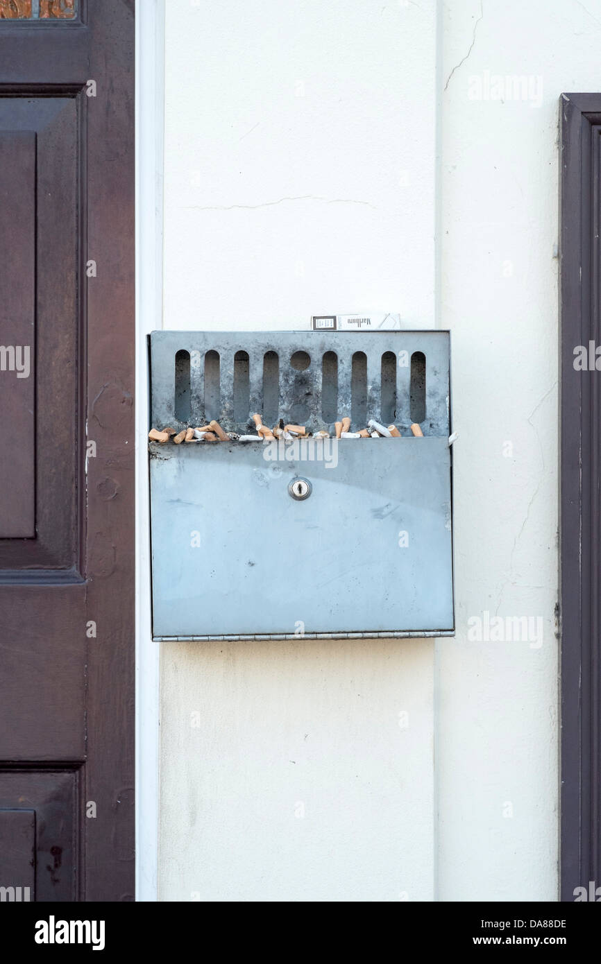 Cigarette ash tray stubber box with cigarette ends and empty packet on ...