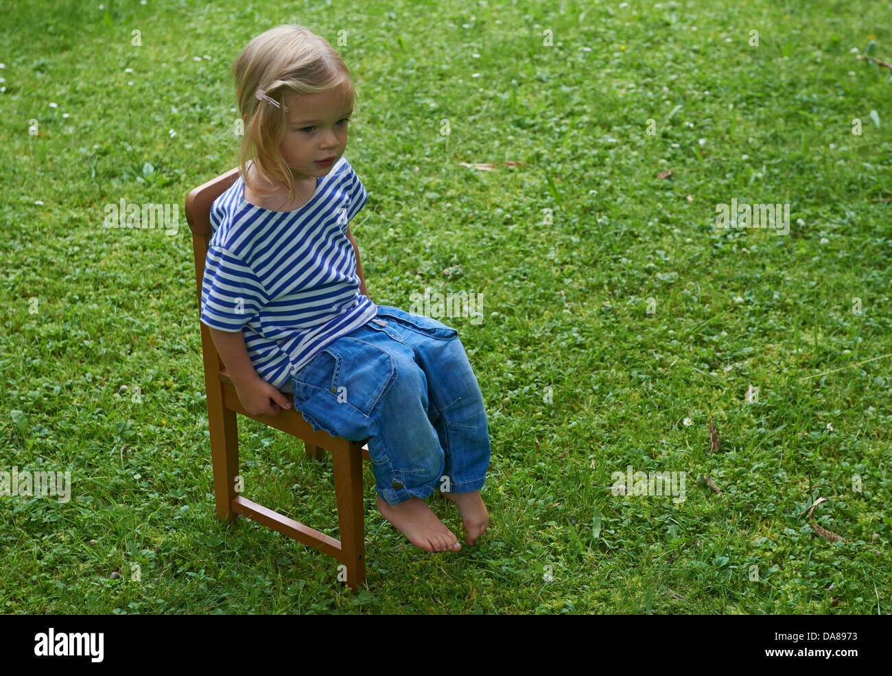 Child girl sitting on little chair, green lawn, outside, garden, summer ...