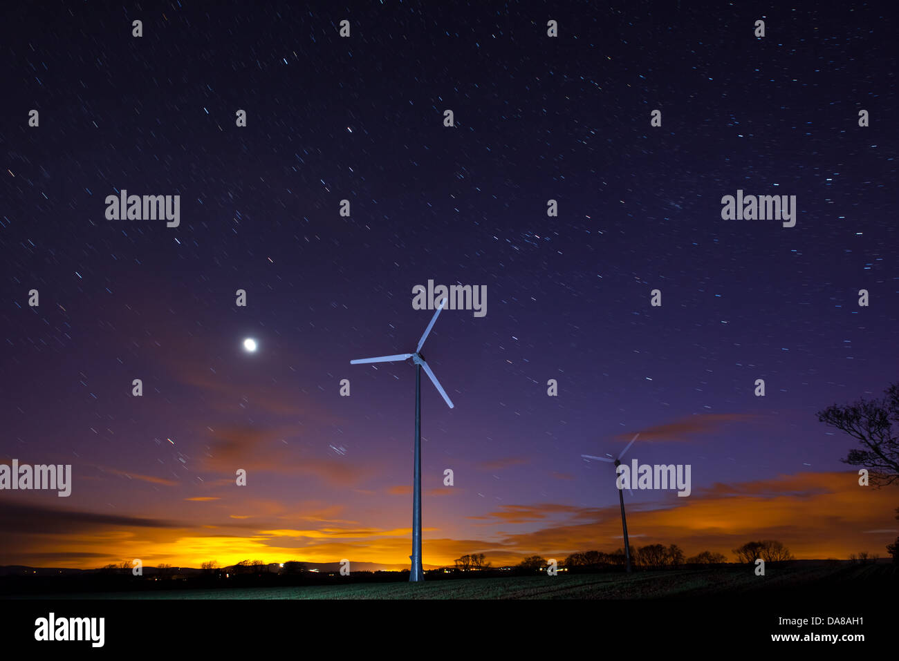 Two wind turbines pictured at sunrise with star trails Stock Photo - Alamy