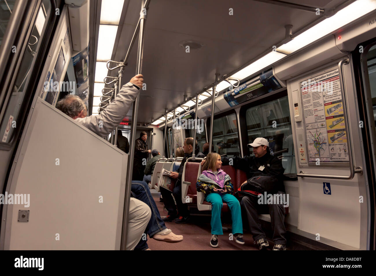 Commuters, a young girl and a man, sit talking on a Metro subway train ...