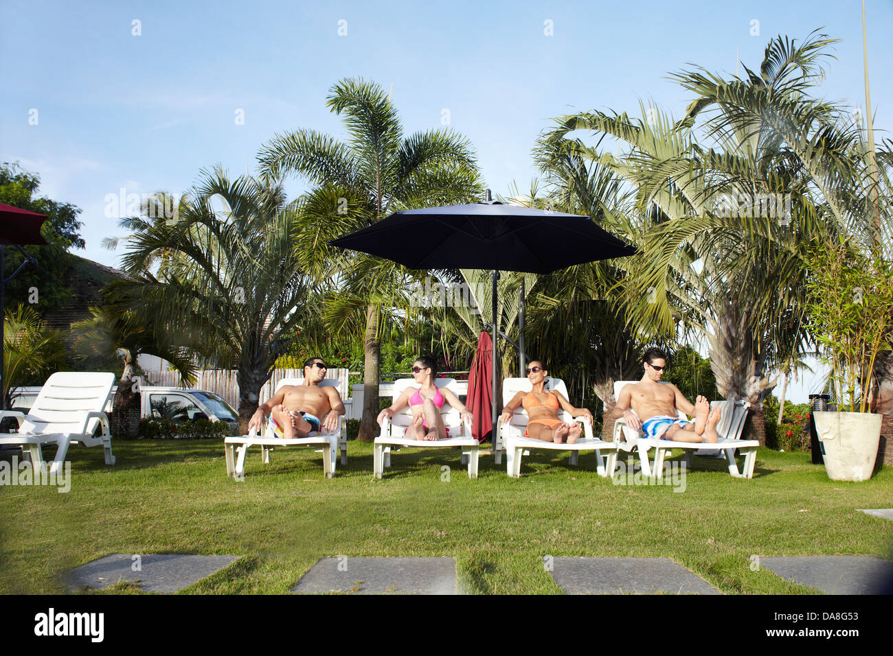 Friends relaxing poolside Stock Photo - Alamy