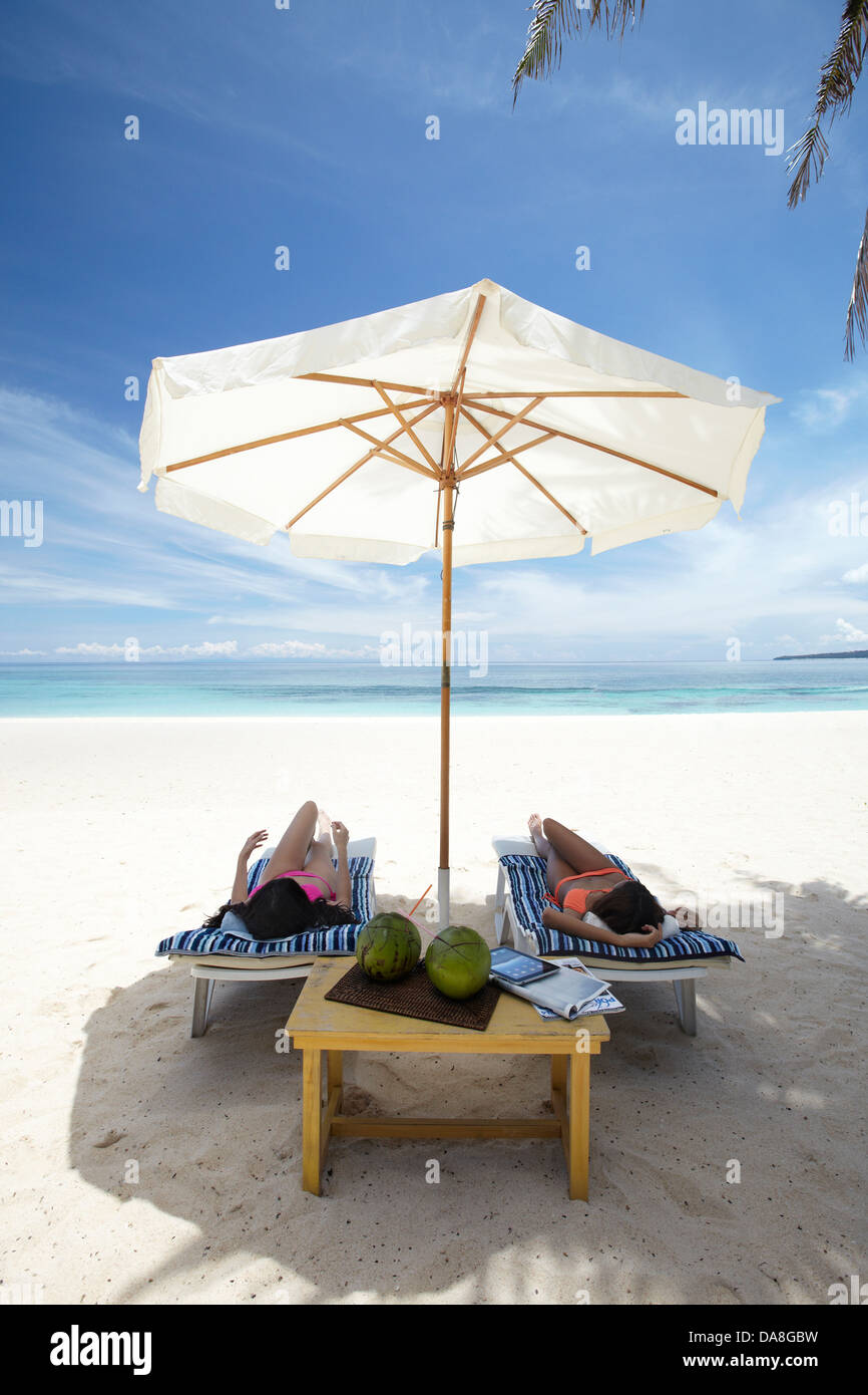 Two women sunbathing on a beach Stock Photo - Alamy