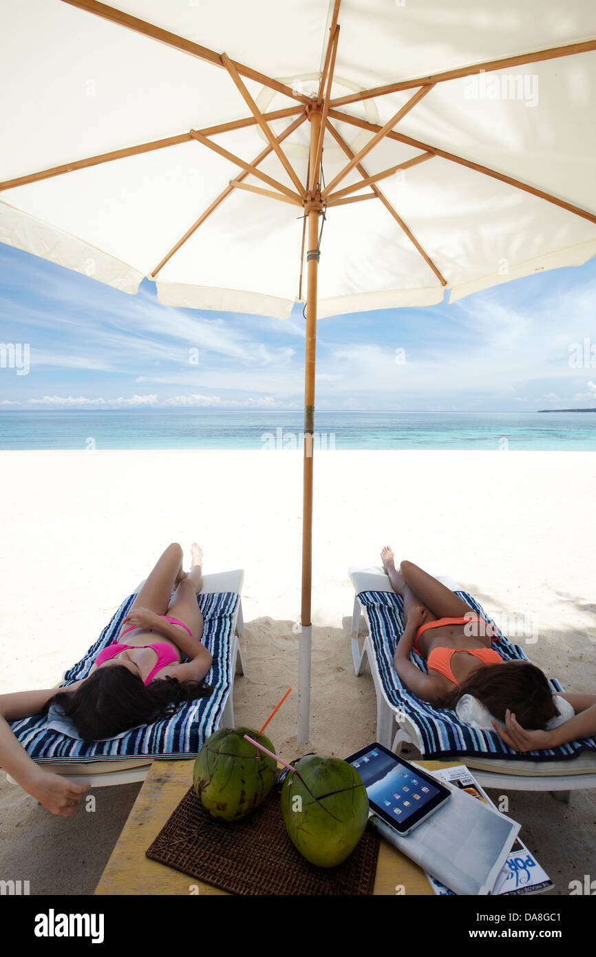 Two women sunbathing on a beach Stock Photo - Alamy