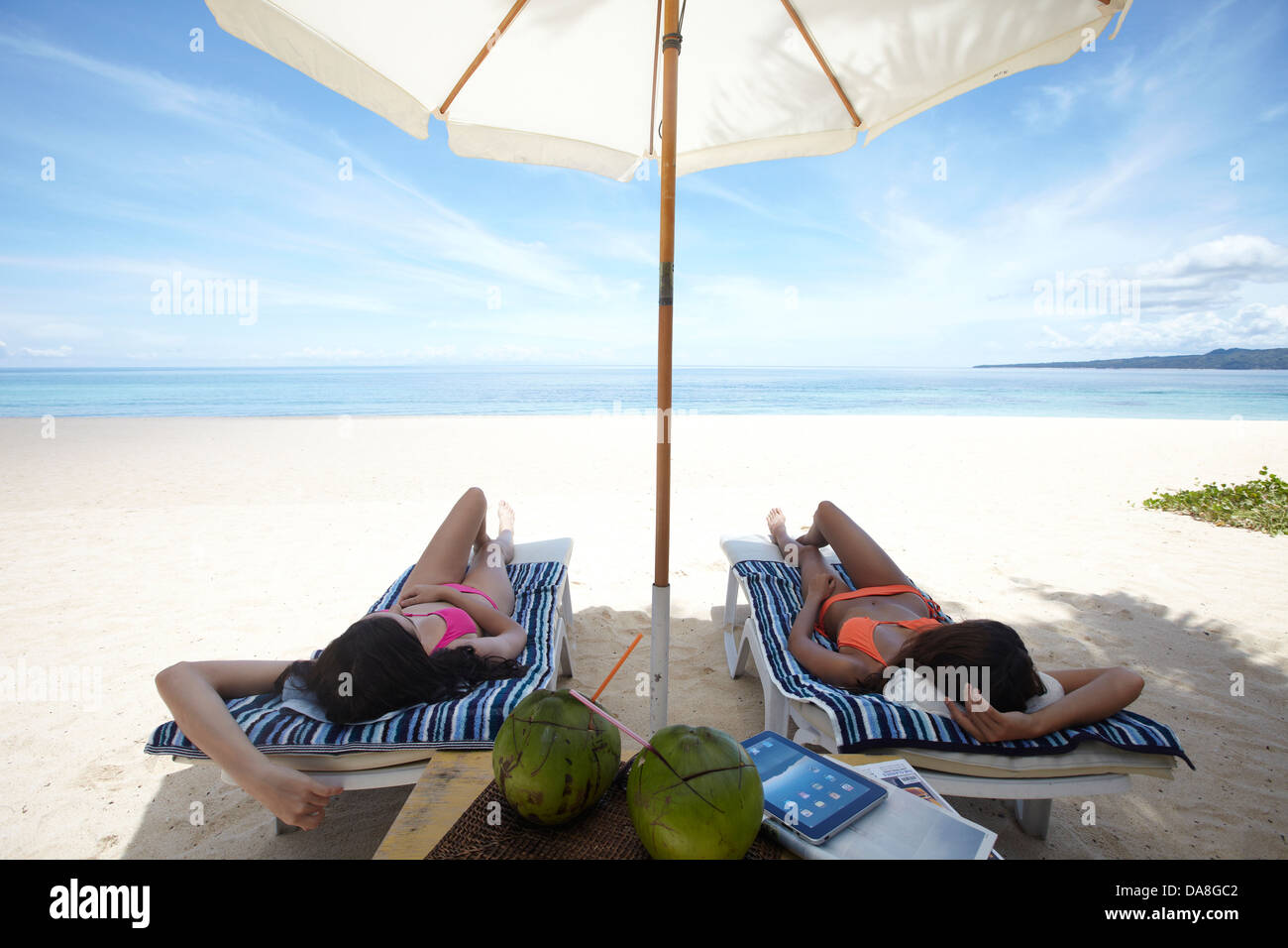 Two women sunbathing on a beach Stock Photo - Alamy