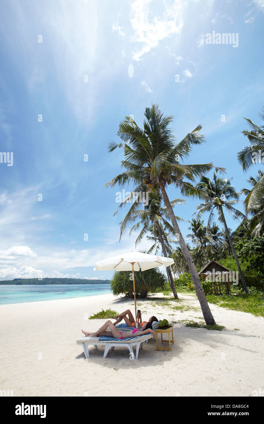 Two women sunbathing on a beach Stock Photo - Alamy