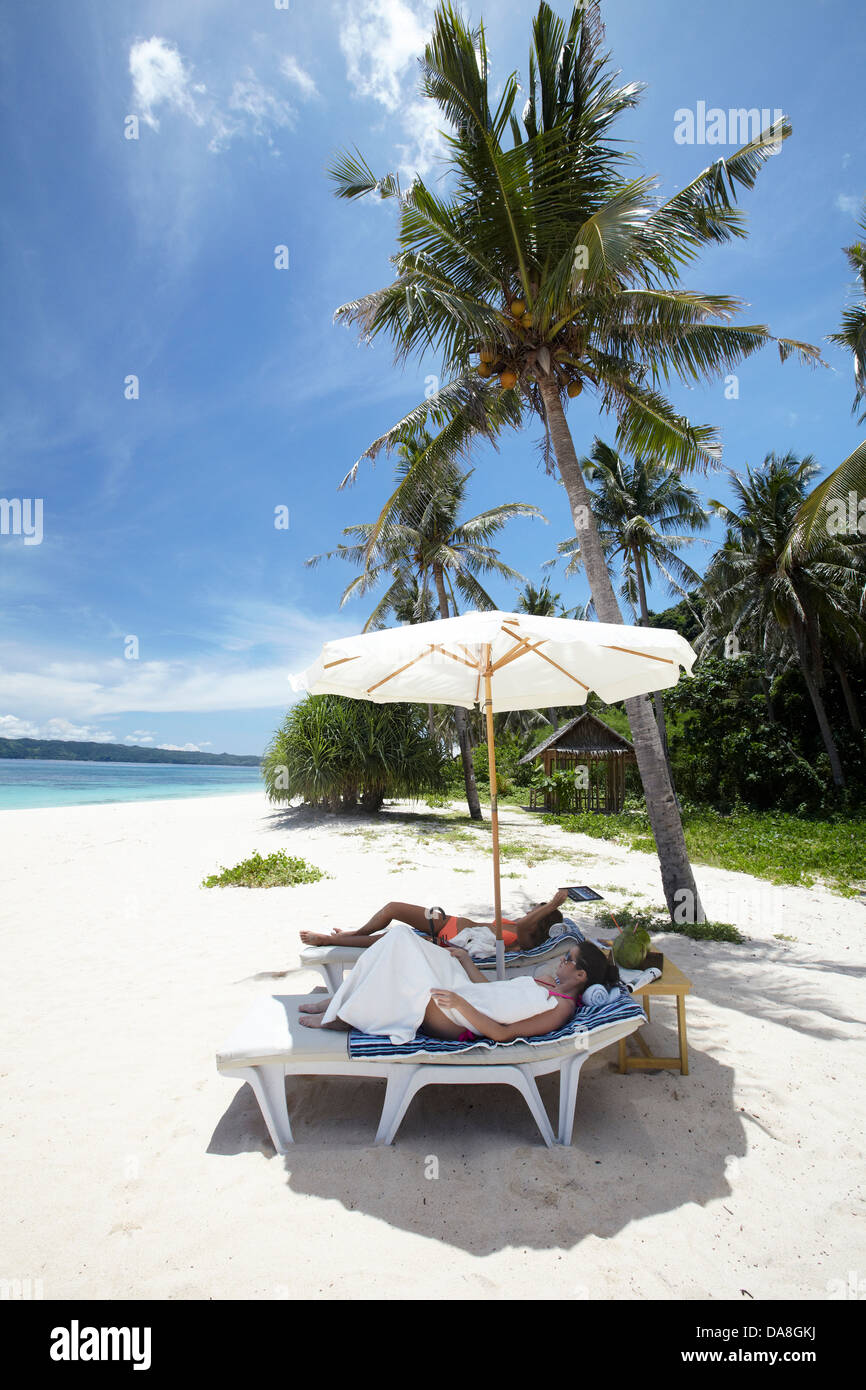 Two woman sunbathing on a beach Stock Photo - Alamy