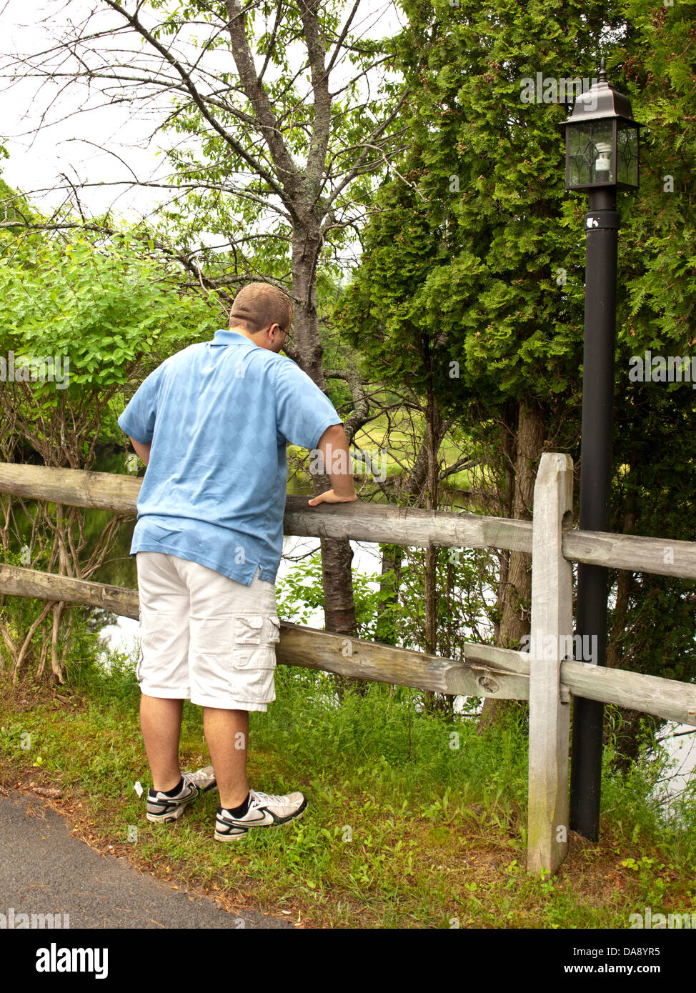 boy looking over wooden fence to see a river Stock Photo - Alamy