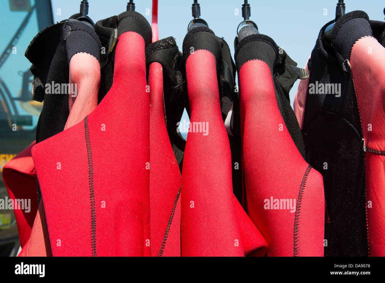 Rack of rubber wetsuits hanging to dry in the sunshine Stock Photo - Alamy