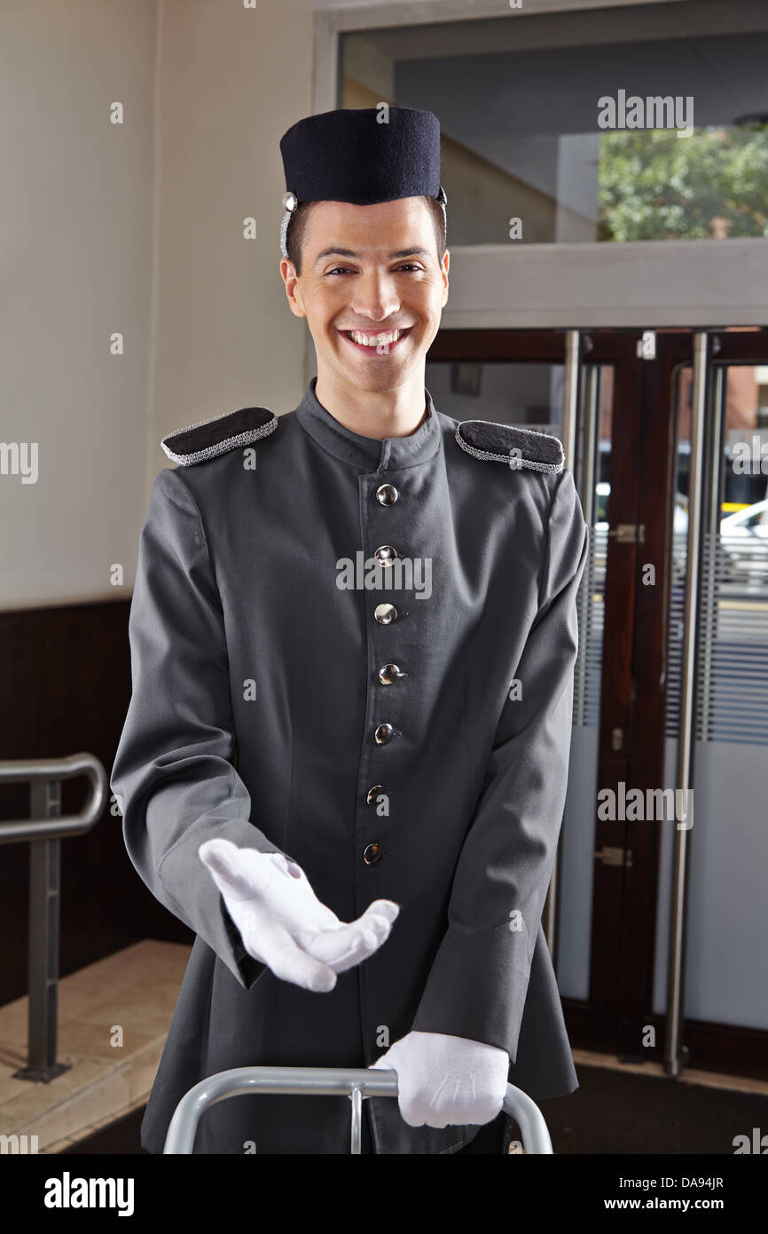 Happy concierge in uniform standing in a hotel lobby Stock Photo - Alamy