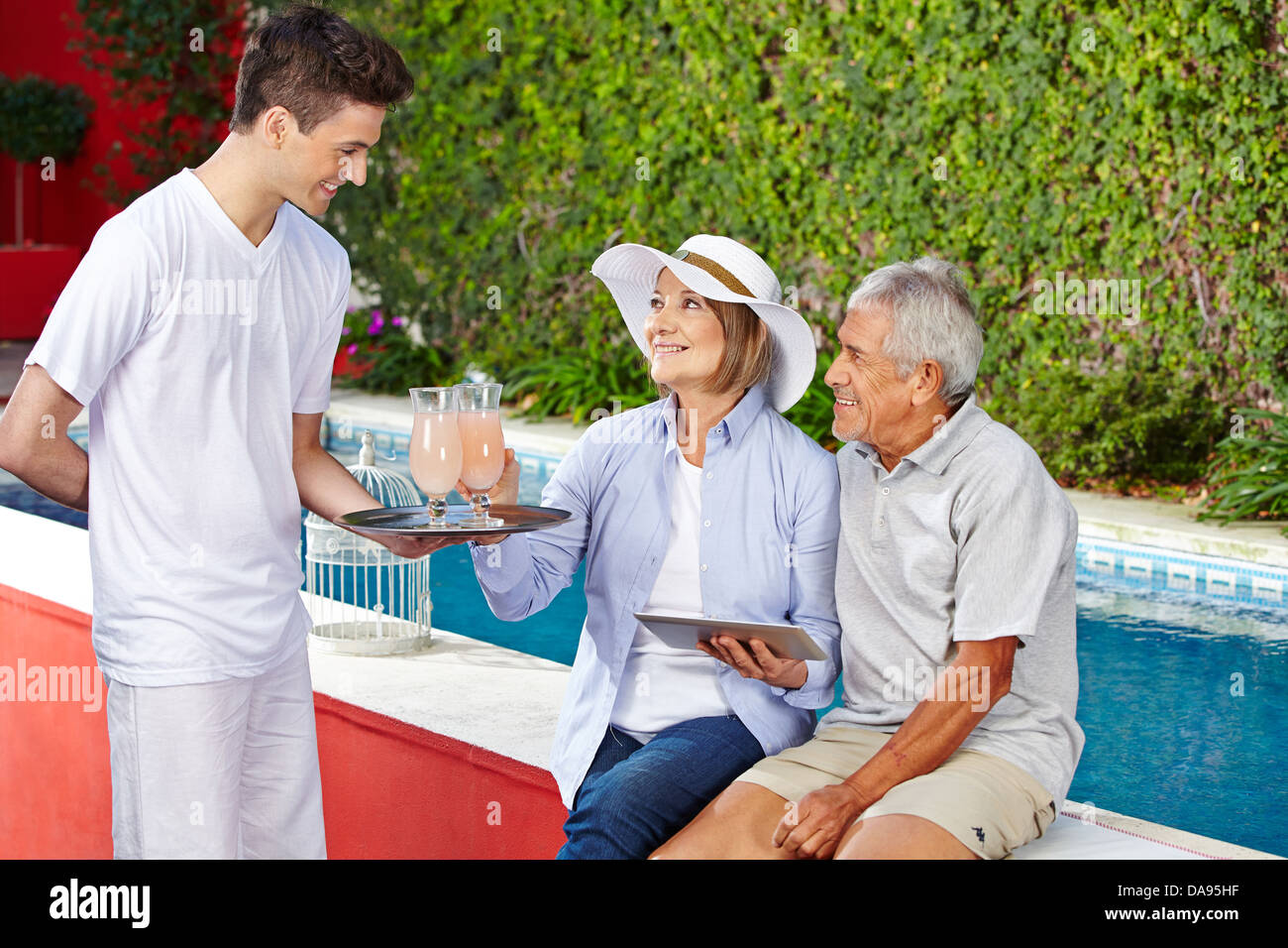Senior couple taking cocktails at hotel pool from waiter Stock Photo ...